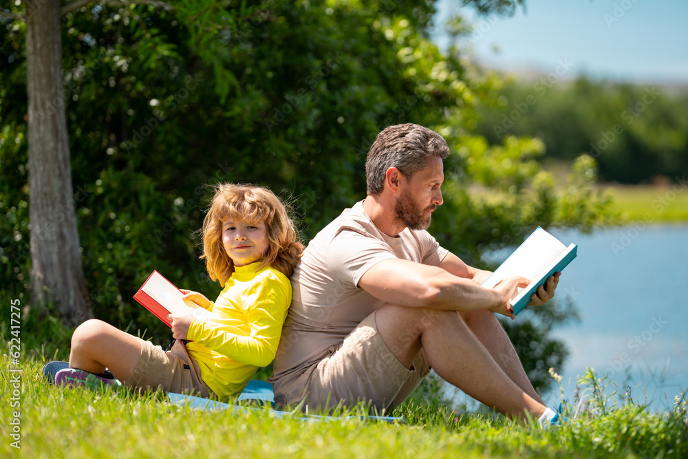 Father read a book with son in a park outdoors. Father and child son ...