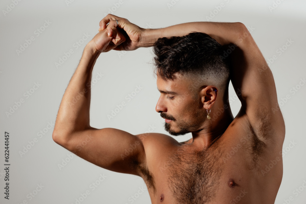 A man flexes his bicep and looks at his strong, lean musculature. His ...