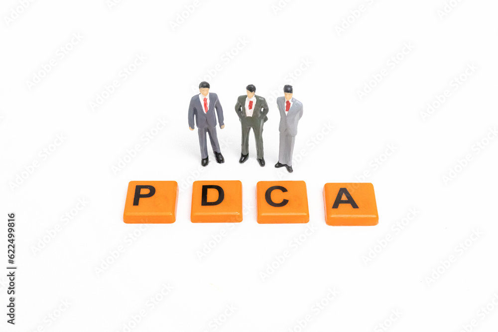 Three miniature businessman look at the PDCA word. PDCA print screen on ...