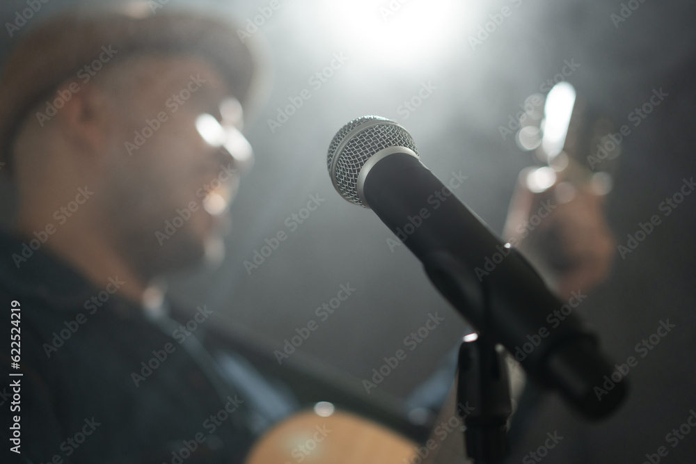Attractive singer man singing music and playing guitar on stage with ...