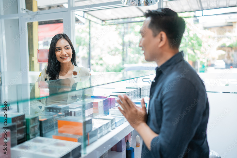 male shopkeeper standing inside the display welcoming the female ...