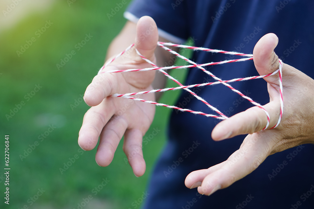 Closeup boy hands is playing rope which called cats cradle game ...