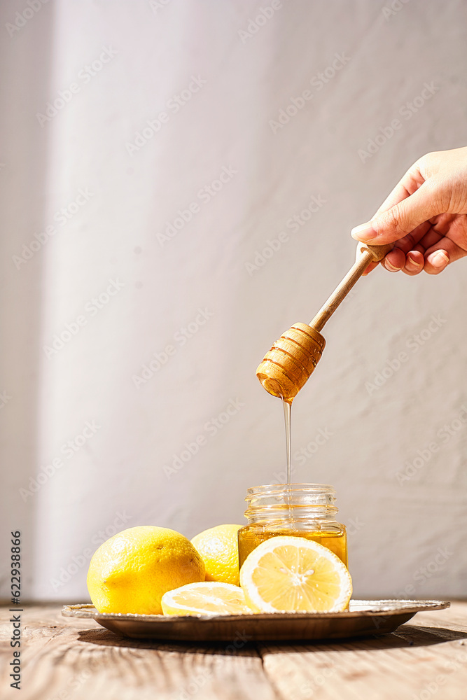 瓶詰めの蜂蜜とそのまわりに置かれたレモン Stock Photo | Adobe Stock
