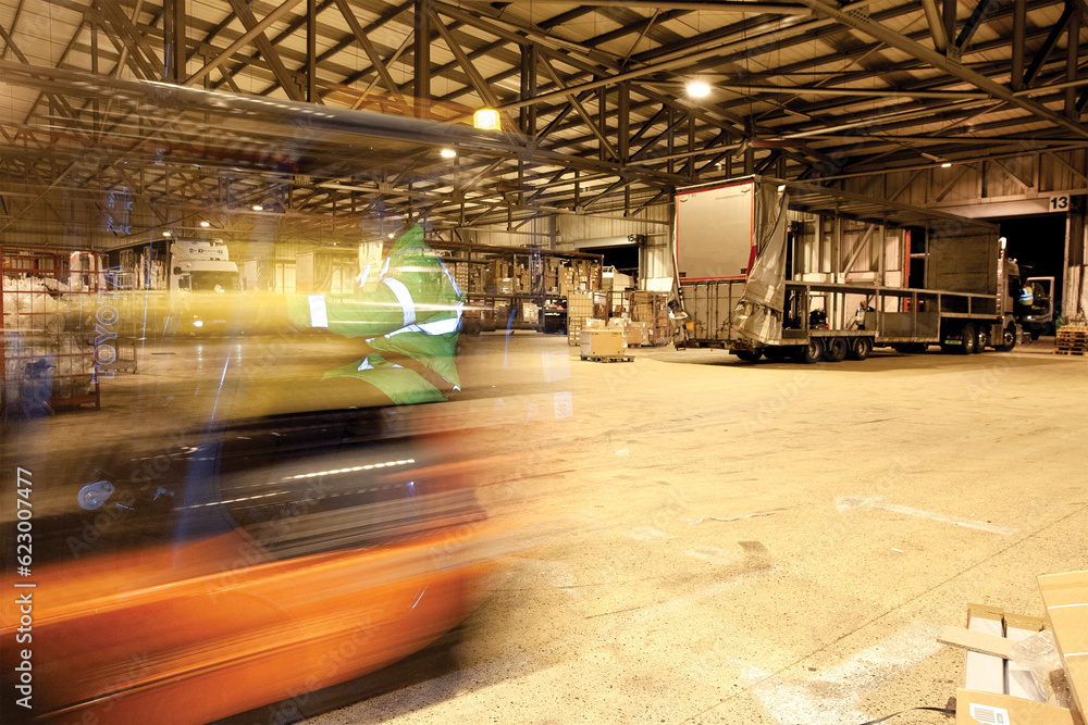 Forklift truck moving around a loading bay with lorry being loaded in ...