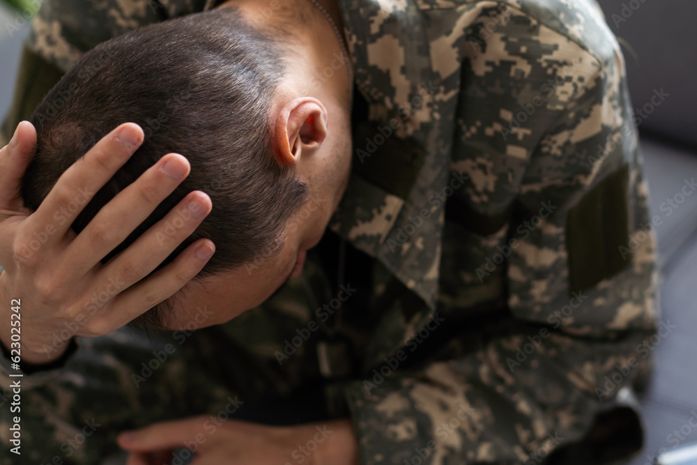 Unhappy man in camouflage uniform sitting at arm chair over white ...