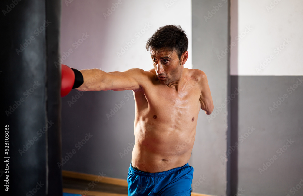 Foto de A shirtless boxer with an amputated arm is punching a punching ...