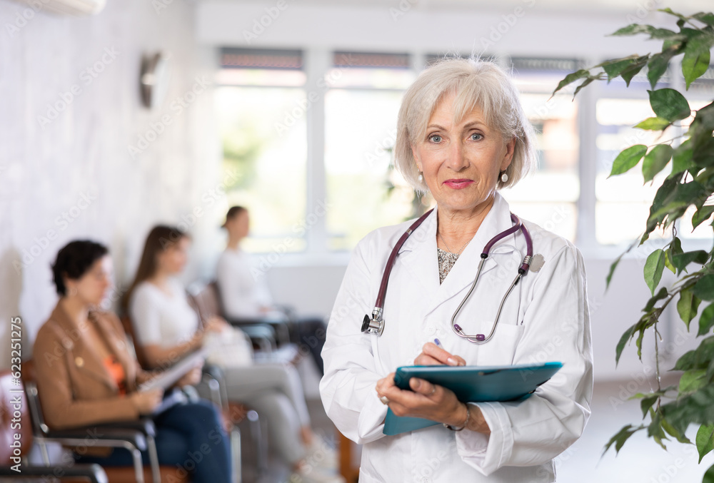 friendly mature female medical employee of clinic in bathrobe is ...