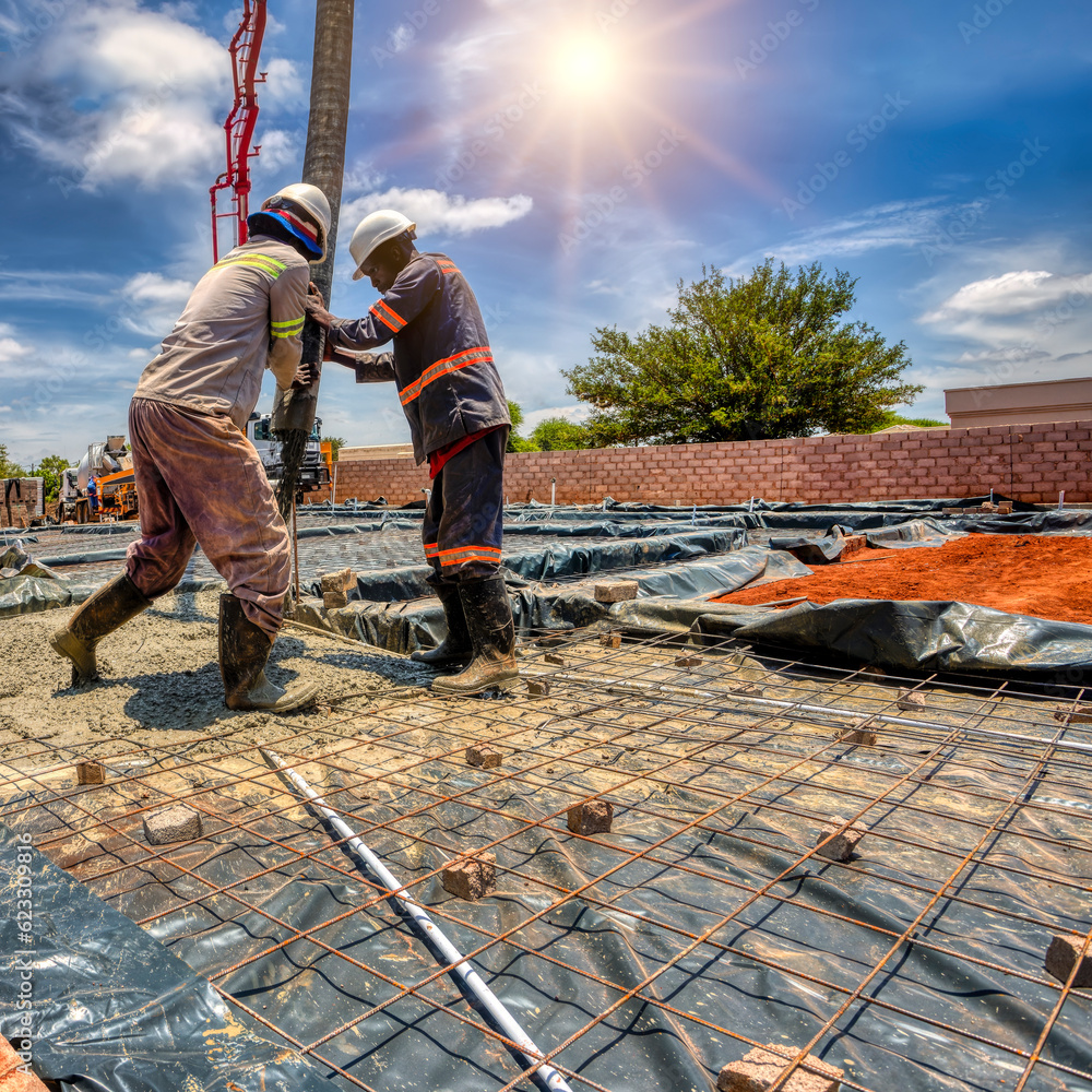 african construction workers using a boom concrete pump to fill the ...