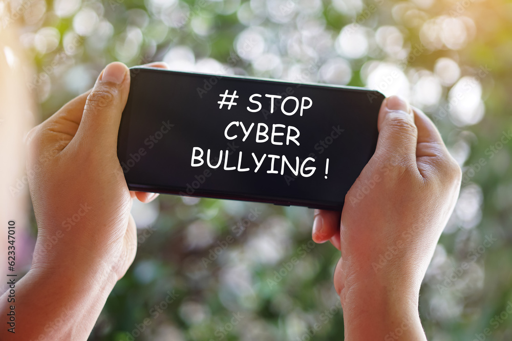 Close up hands holds smartphone with word # Stop cyber bullying on ...