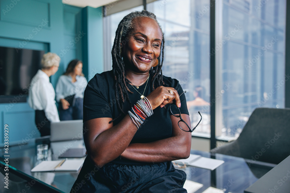 Black female professional sitting on a boardroom table in a business ...