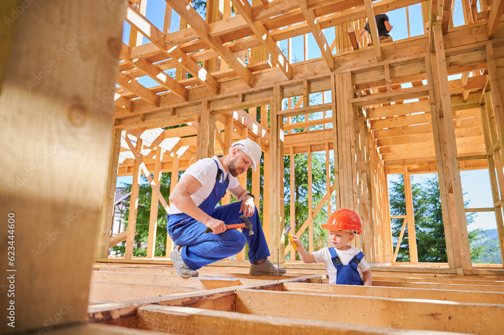 Father with toddler son constructing wooden frame house. Man builder ...