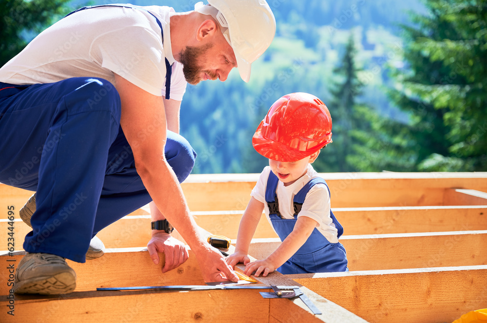Father with toddler son building wooden frame house. Male worker ...