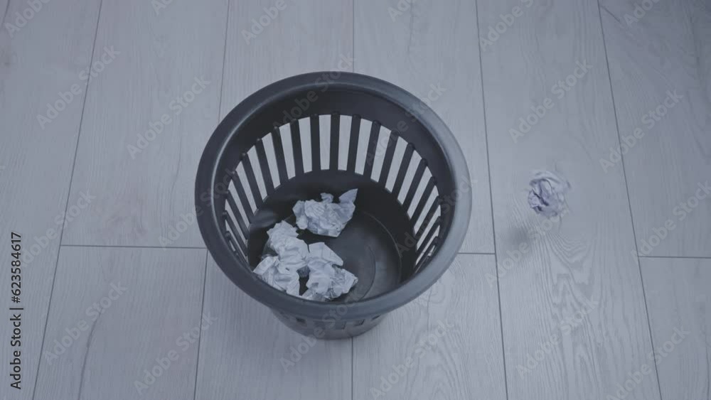 Stack of crumpled paper falling into trash can on white parquet floor ...