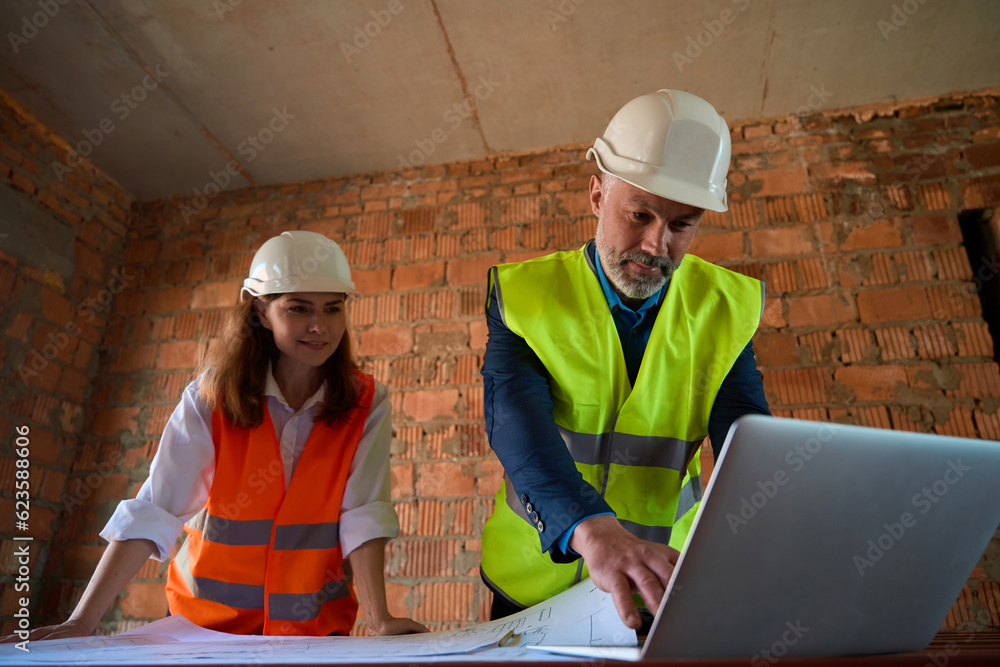 Builders entering measurements of building blueprint to make 3d layout ...
