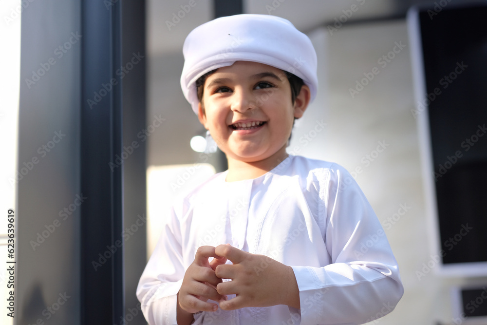 Happy boy in Kandura looking far with business, mall or school ...
