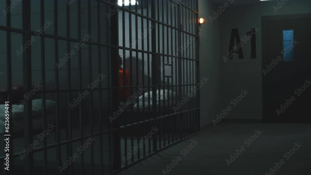 Guilty criminals in orange uniforms lay and sit on the beds in prison ...