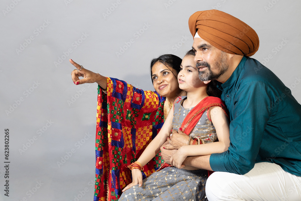 Portrait of Indian sikh Family together pointing towards the right ...