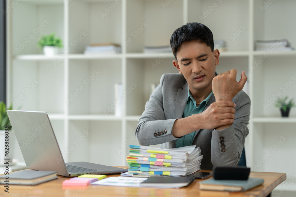 The arm of a young businessman holding his wrist, arm, neck from pain ...