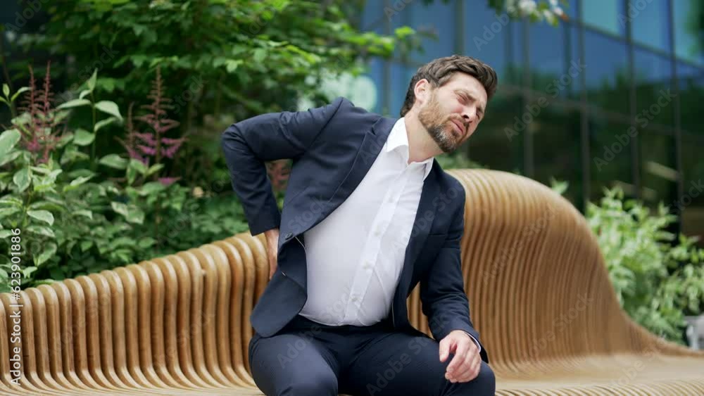 Tired entrepreneur businessman having severe back pain ache sitting on ...