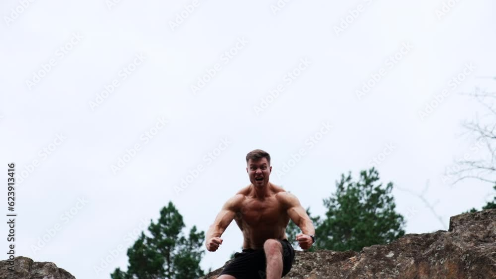 Caucasian strongman demonstrating his muscles standing on the rock ...
