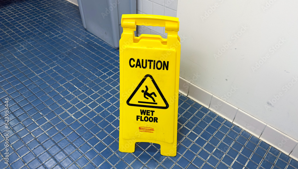 Bright yellow caution sign with 'wet floor' text symbolizes potential ...