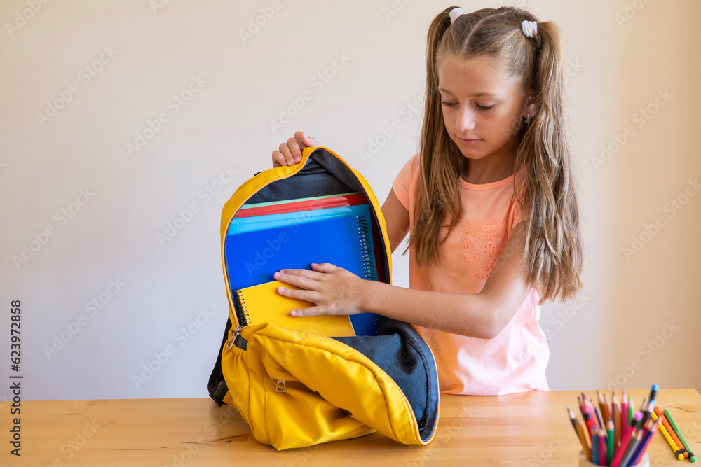 Blonde Elementary School Girl With Pigtails Puts Office Supplies Into A ...