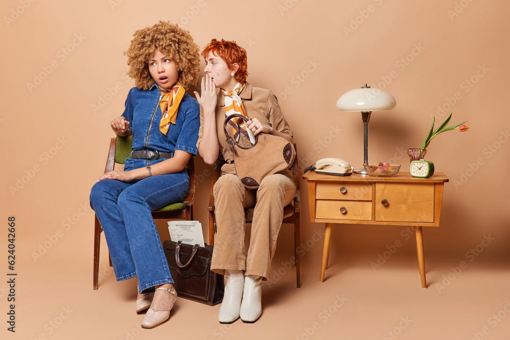Women friends or colleagues wearing vintage outfits whisper secret and ...