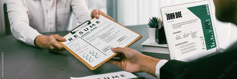 Suit-clad candidate hand over resume to interviewers during job ...