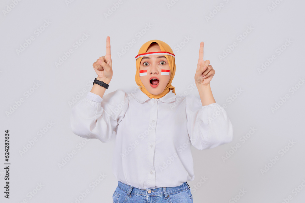 Surprised young Asian Muslim woman wearing hijab pointing her finger up ...
