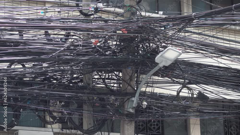 Messy power wires are tangled on the electrical pole, creating a ...