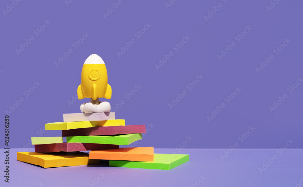 Yellow rocket stands on desk on top of pile of sticky notes summit ...