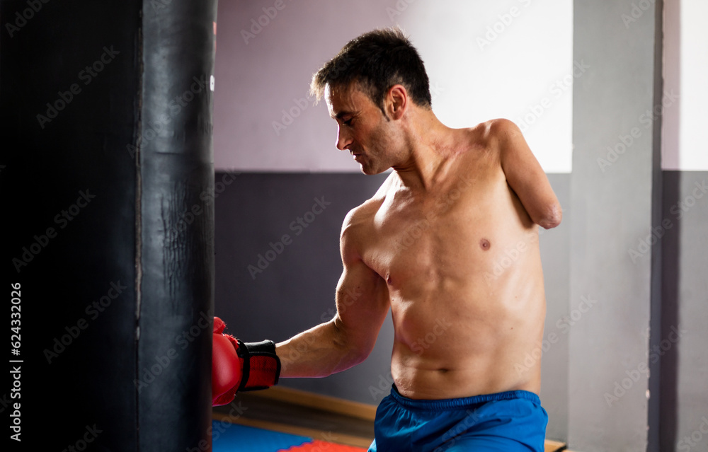 A shirtless boxer with an amputated arm is punching the bottom of a ...