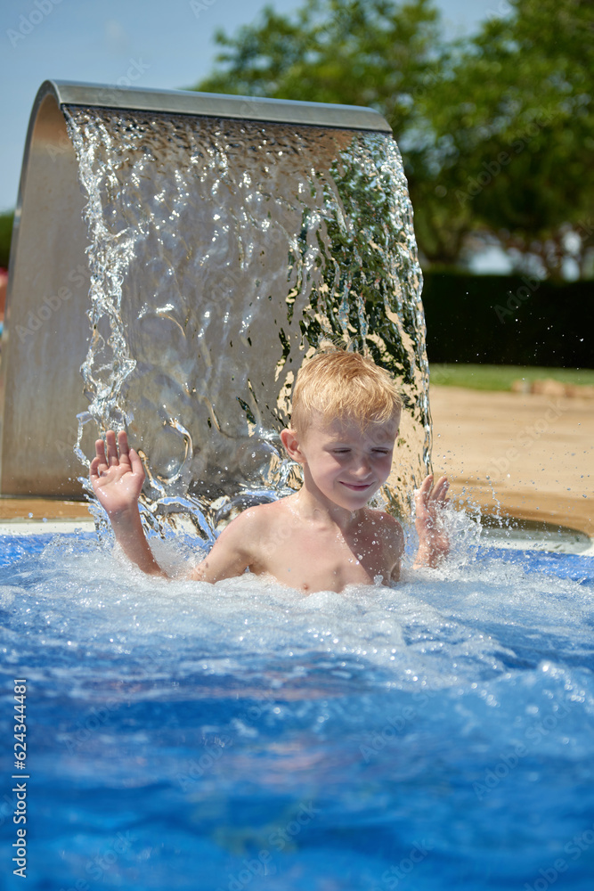 Young boy kid child eight years old splashing in swimming pool having ...