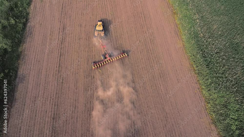 Shooting from drone flying over tractor with harrow plowing ground on ...