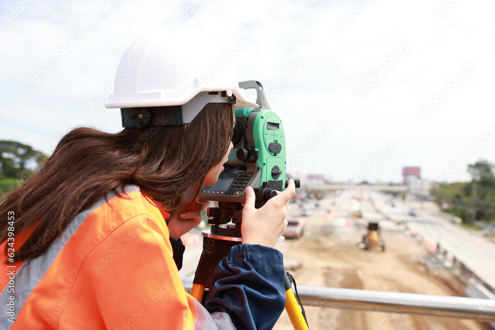 Site female engineer operating her instrument during roadworks. Builder ...