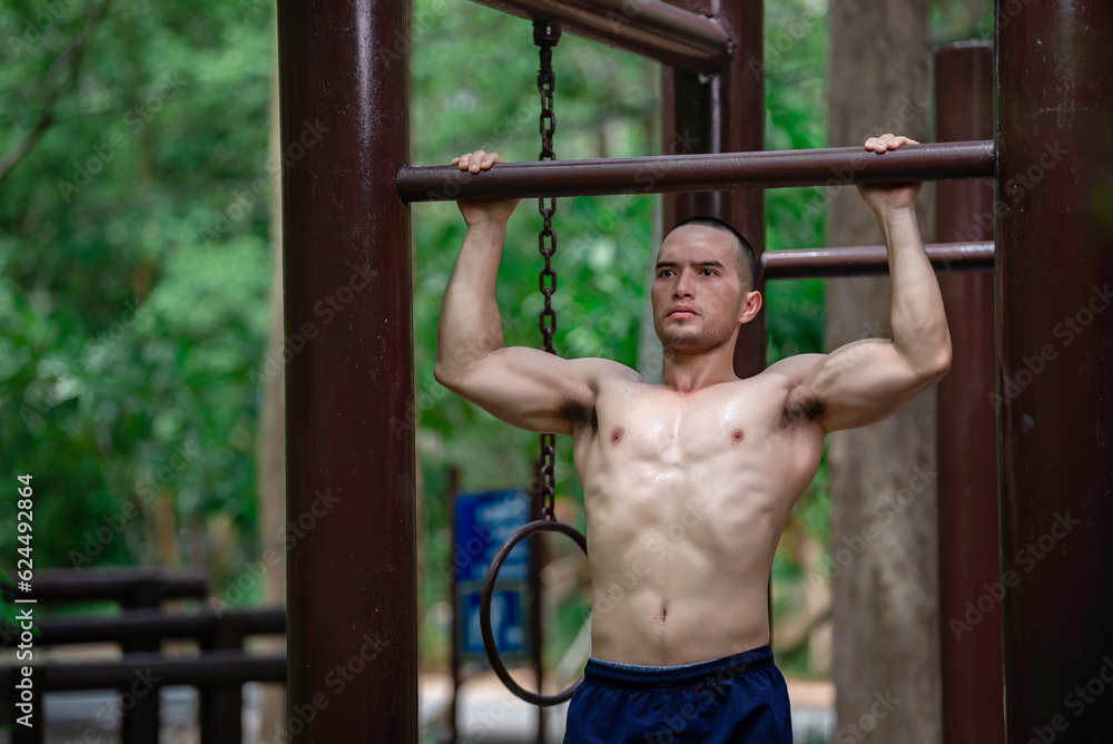 Handsome man exercises by hanging on a bar outdoor, Asian man trains ...