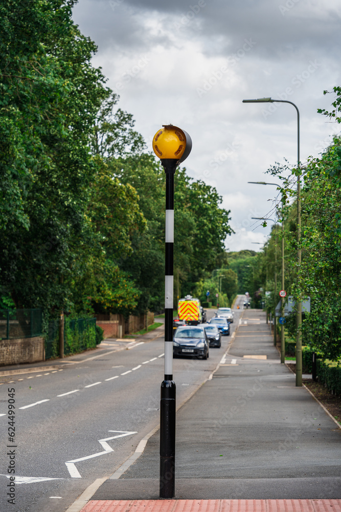 Alerting yellow traffic light at crosswalk on English road, against ...