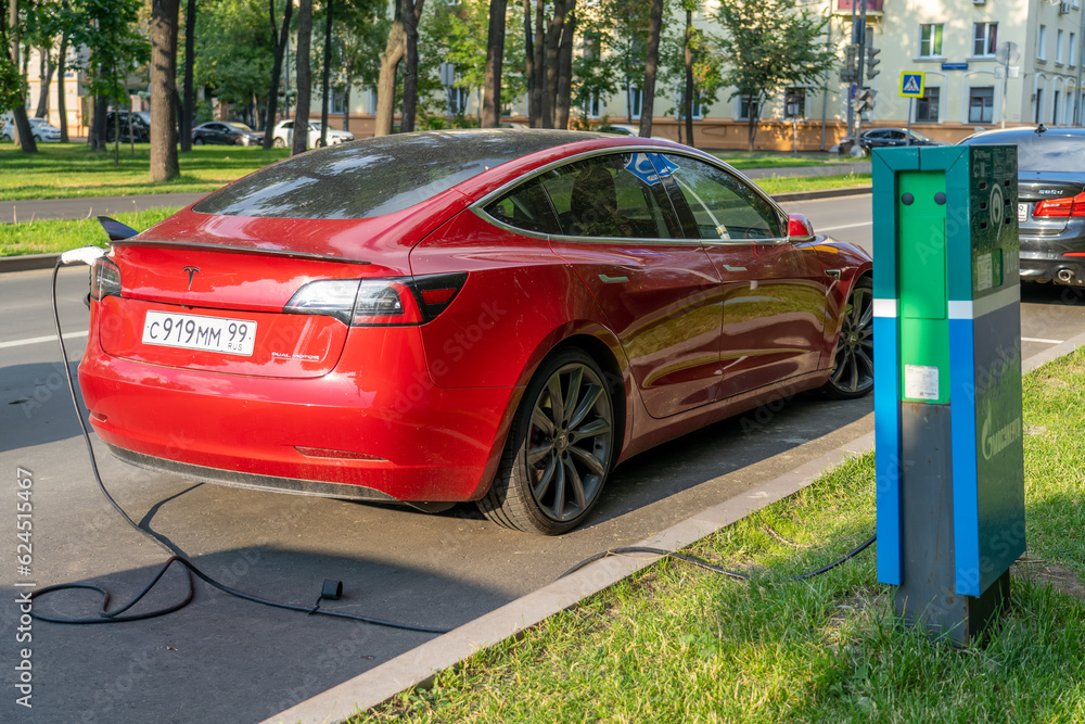 Moscow, Russia - July 23 2022: Red Tesla car is charging battery on ...