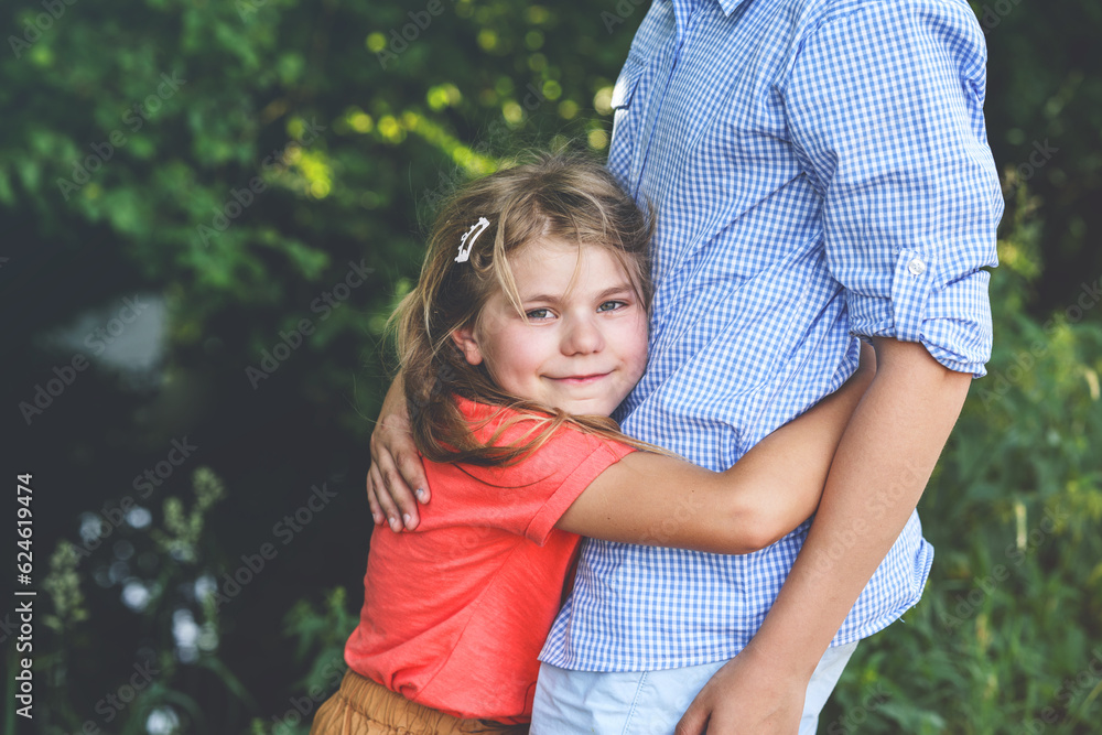 An upset little girl finds comfort in the embrace of her caring teenage ...