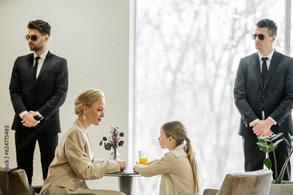 bodyguards standing near female clients, preteen girl and blonde mother ...