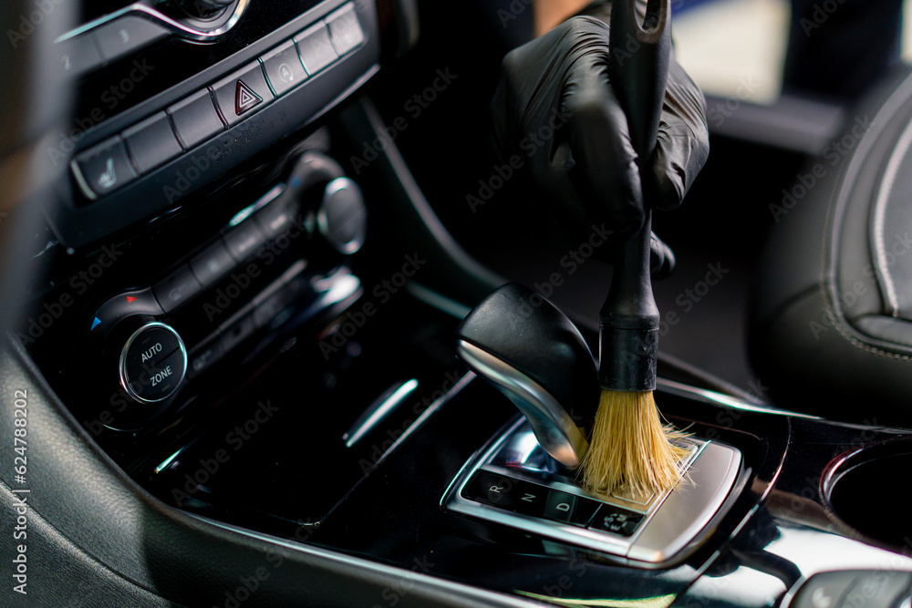 Car wash worker thoroughly cleaning the interior of a luxury car with a ...