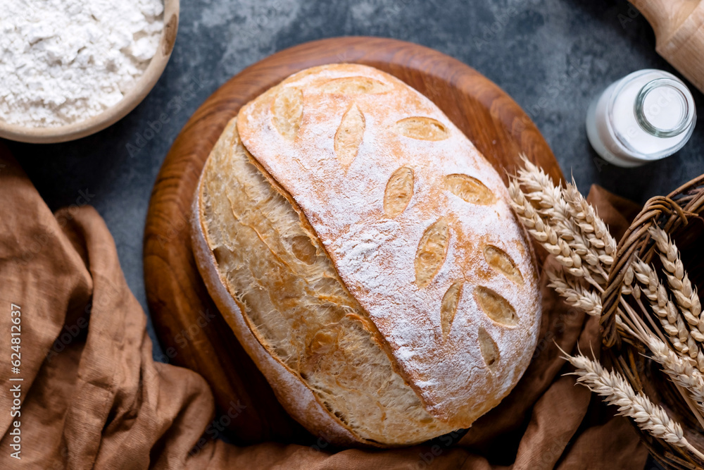 Freshly baked wholemeal bread with ingredients and ears of wheat on a ...