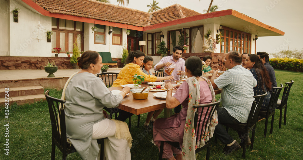 Happy Extended Indian Family Eating Together Outdoors in House Backyard ...