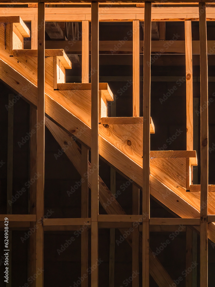 Side view of a new wooden staircase, with wall studs on either side ...