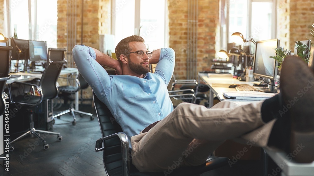 Work done. Side view of satisfied bearded young man in eyeglasses and ...