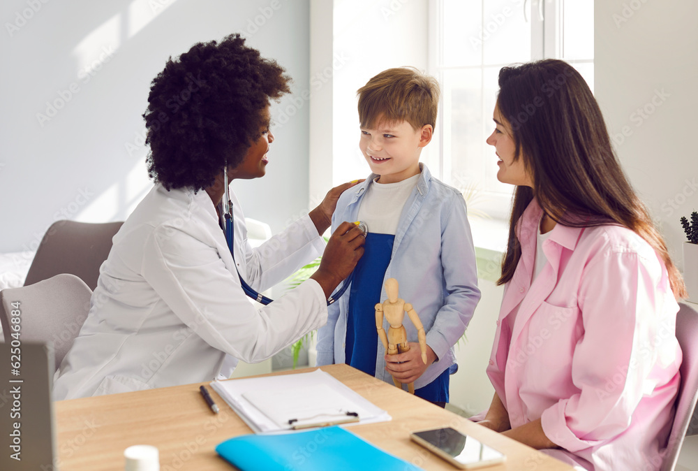 African female pediatrician examining boy patient with stethoscope ...