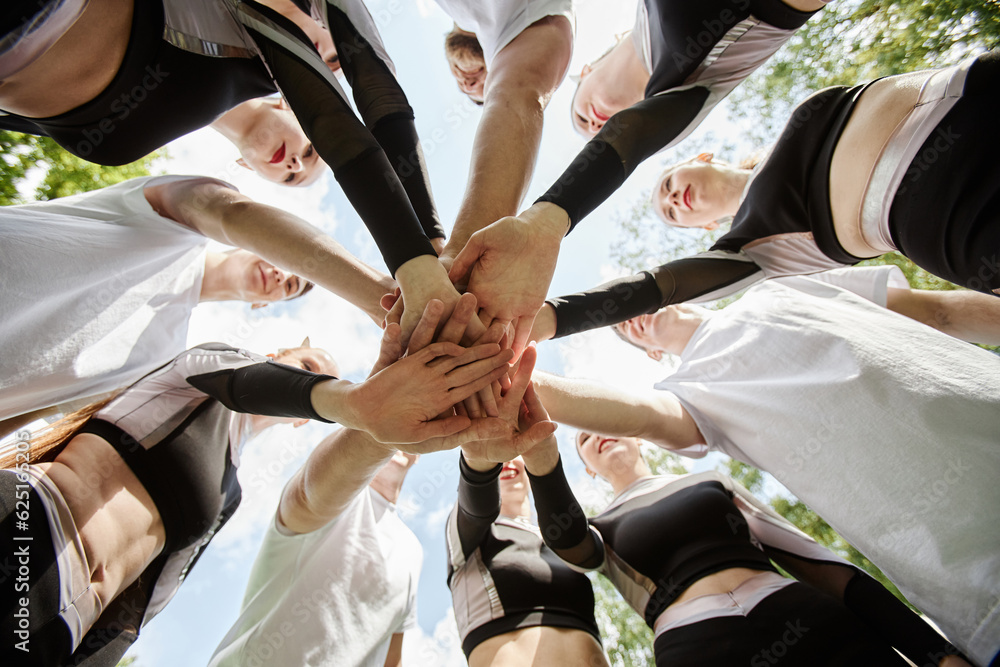 Low angle view of cheerleader team holding hands and supporting each ...