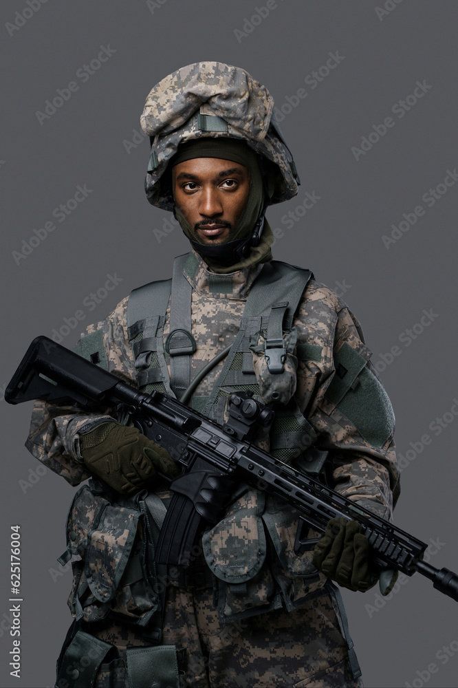 Confident soldier in NATO uniform and helmet poses with his rifle on a ...