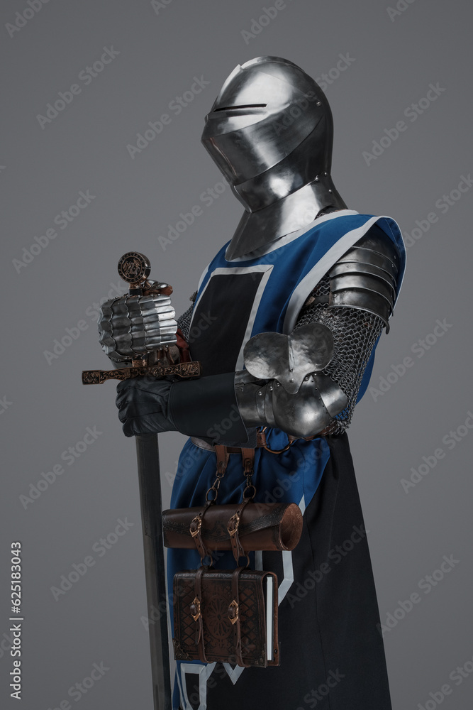 A medieval soldier garbed in blue surcoat and armor holding a sword ...