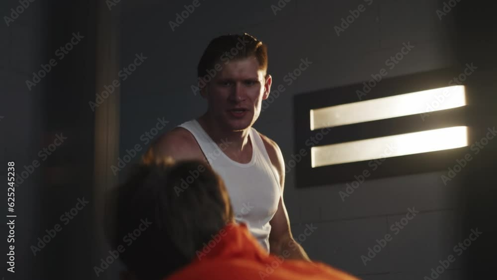Male prisoners fight in prison cell. Criminals in orange uniforms talk ...